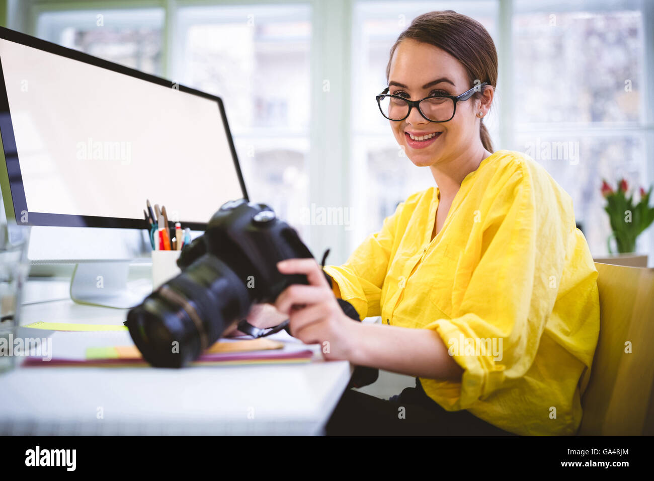 Portrait of confident photographer with camera at creative office Stock ...