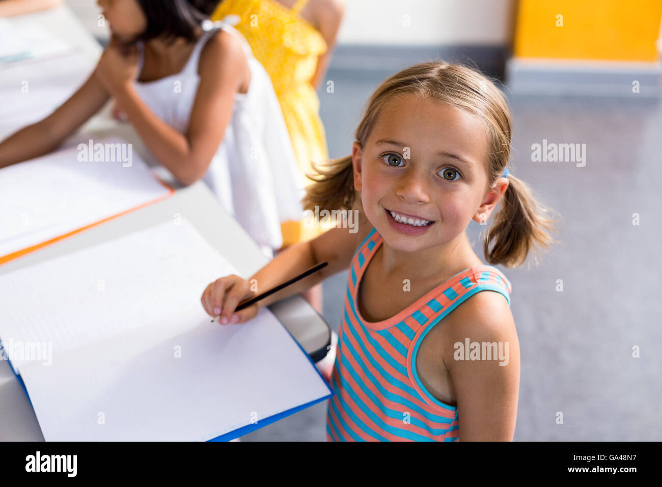 Portrait of happy girl writing on book Stock Photo - Alamy