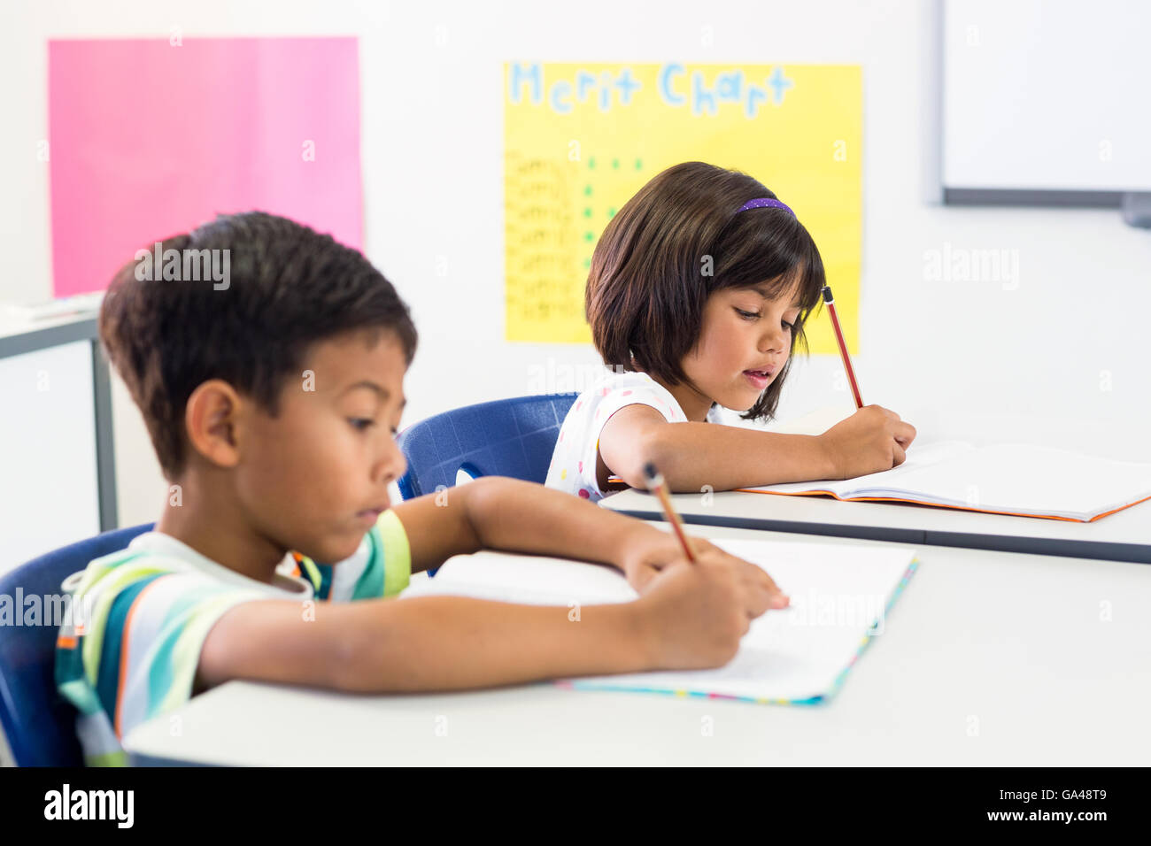 Schoolchildren writing on books Stock Photo - Alamy