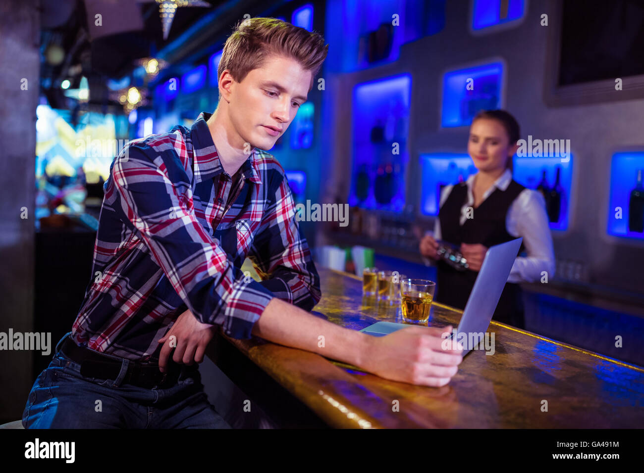 Man using laptop at bar counter with bartender working Stock Photo - Alamy