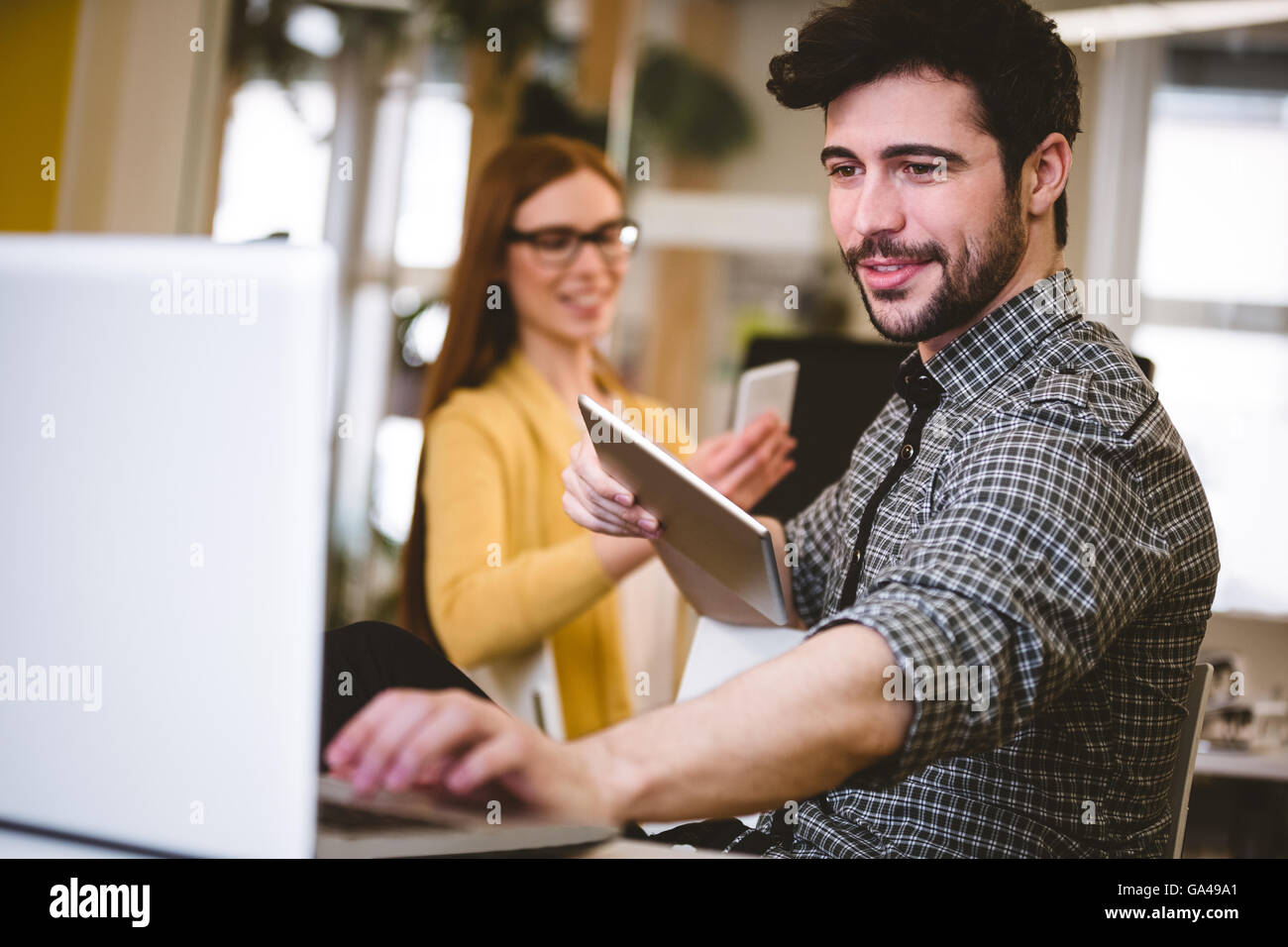 Businessman using laptop with female coworker Stock Photo - Alamy