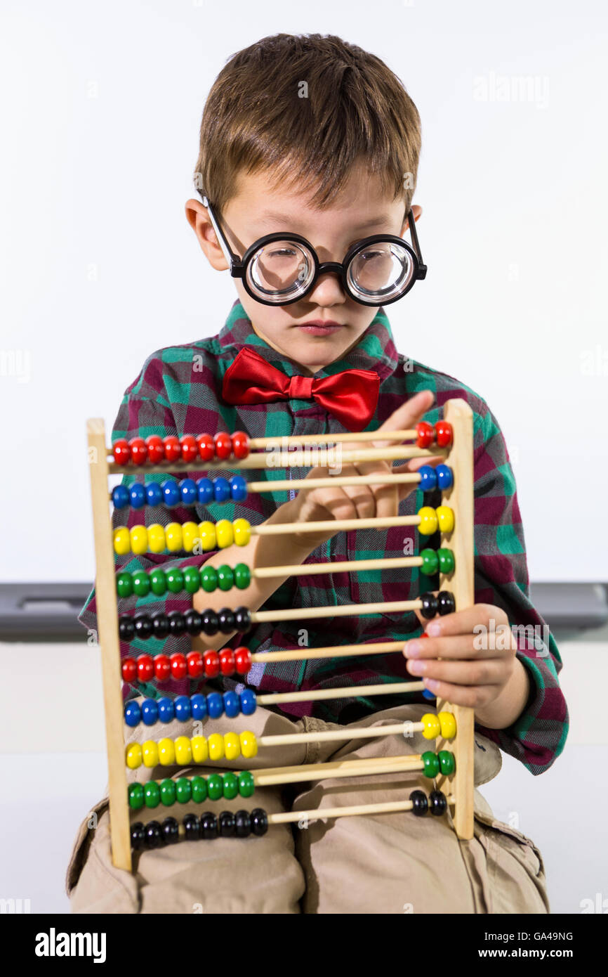 Cute boy playing with abacus against whiteboard in classroom Stock ...