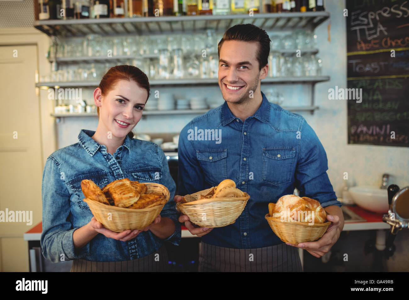 Portrait of cheerful baristas offering breads at coffee shop Stock ...