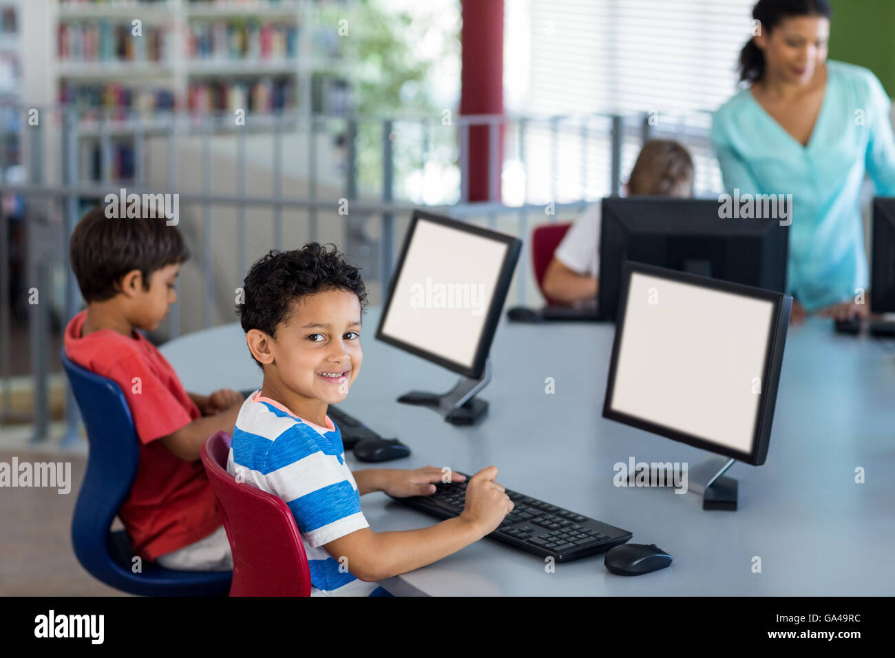 Boy with classmates and teacher during computer class Stock Photo - Alamy