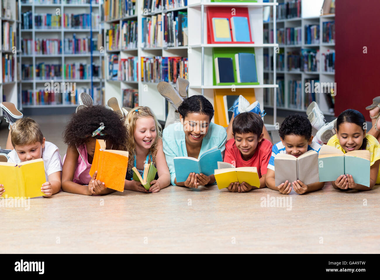 Teacher with students reading books while lying down Stock Photo - Alamy