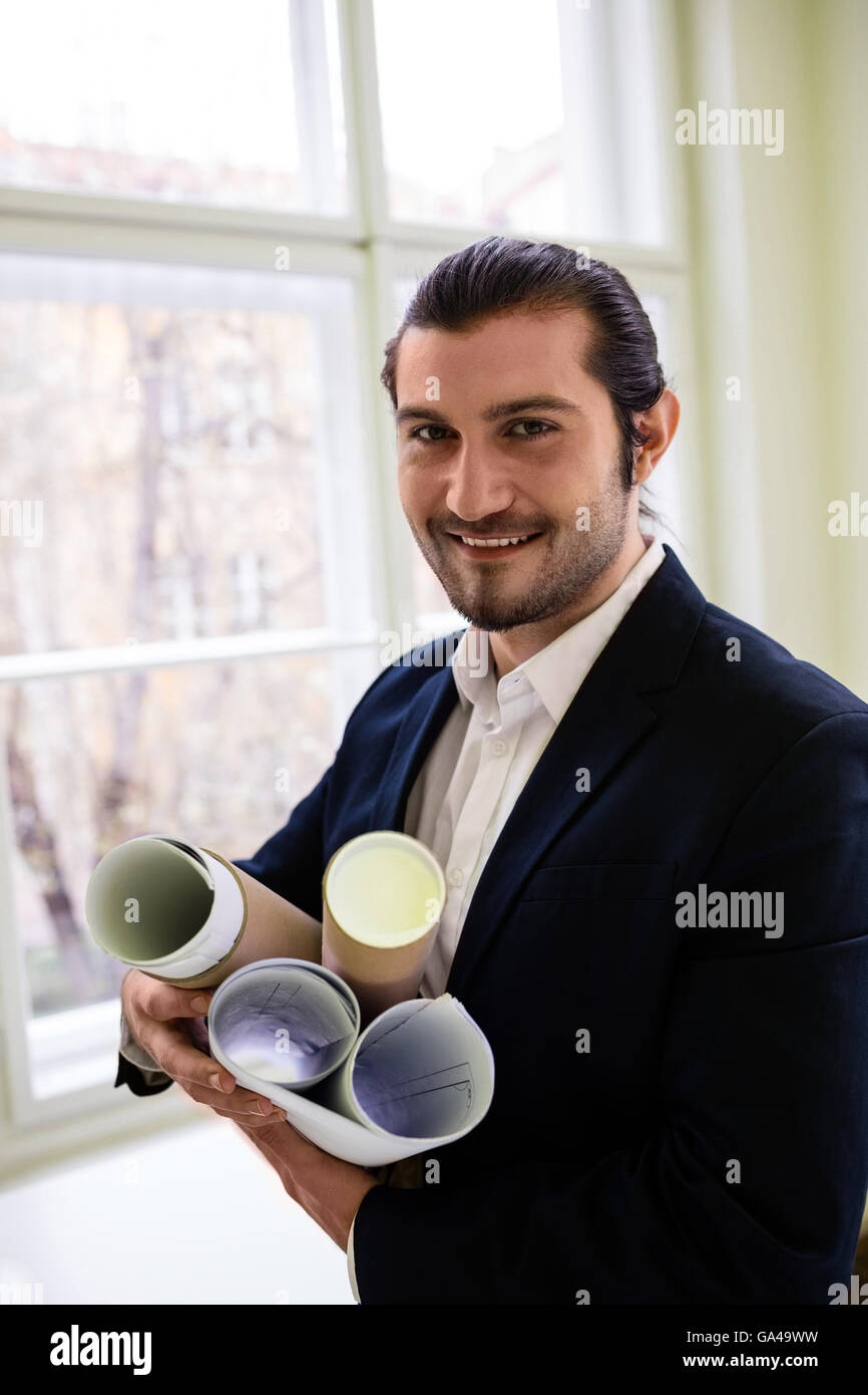 Smiling interior designer holding blueprints Stock Photo - Alamy