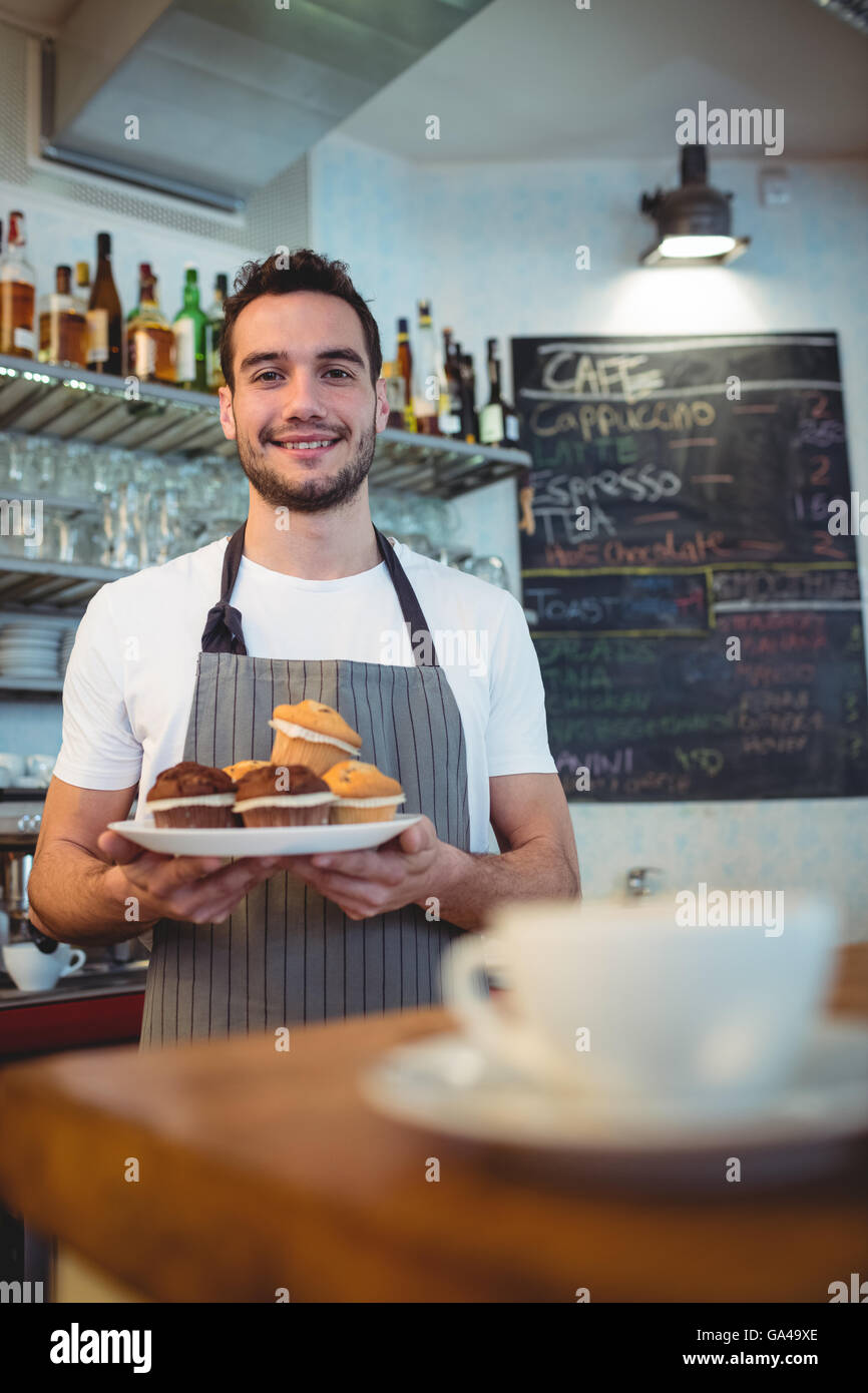 Portrait of confident waiter with cupcakes at coffee house Stock Photo ...