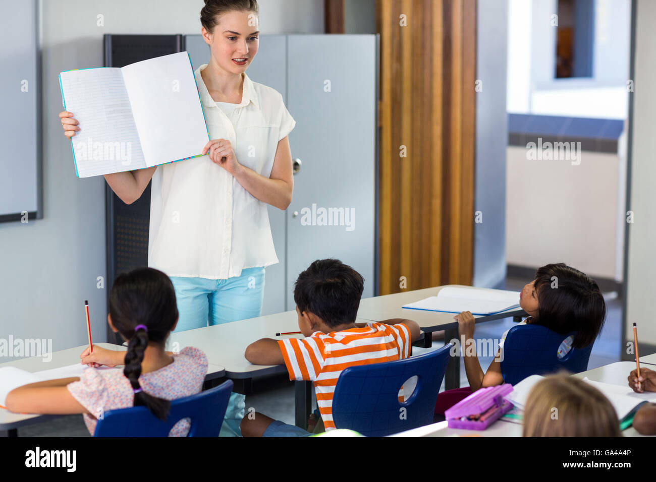 Teacher showing book with children Stock Photo - Alamy