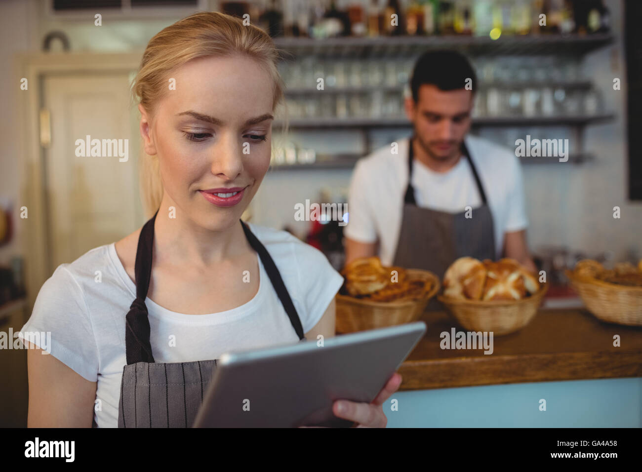 Waitress using tablet computer with colleague in background Stock Photo ...