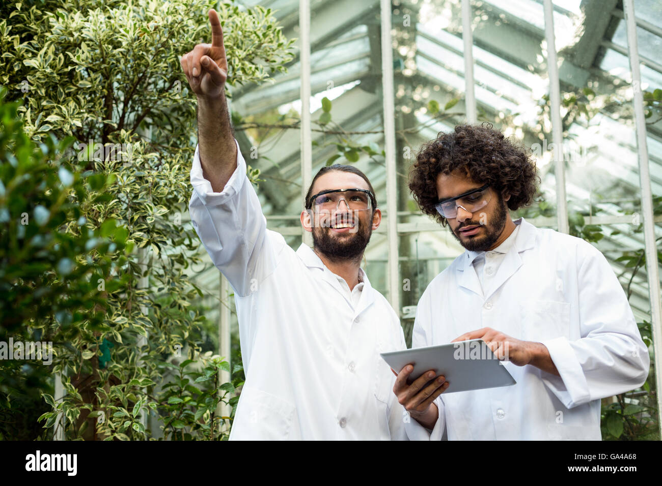 Male scientist pointing while colleague using digital tablet Stock ...