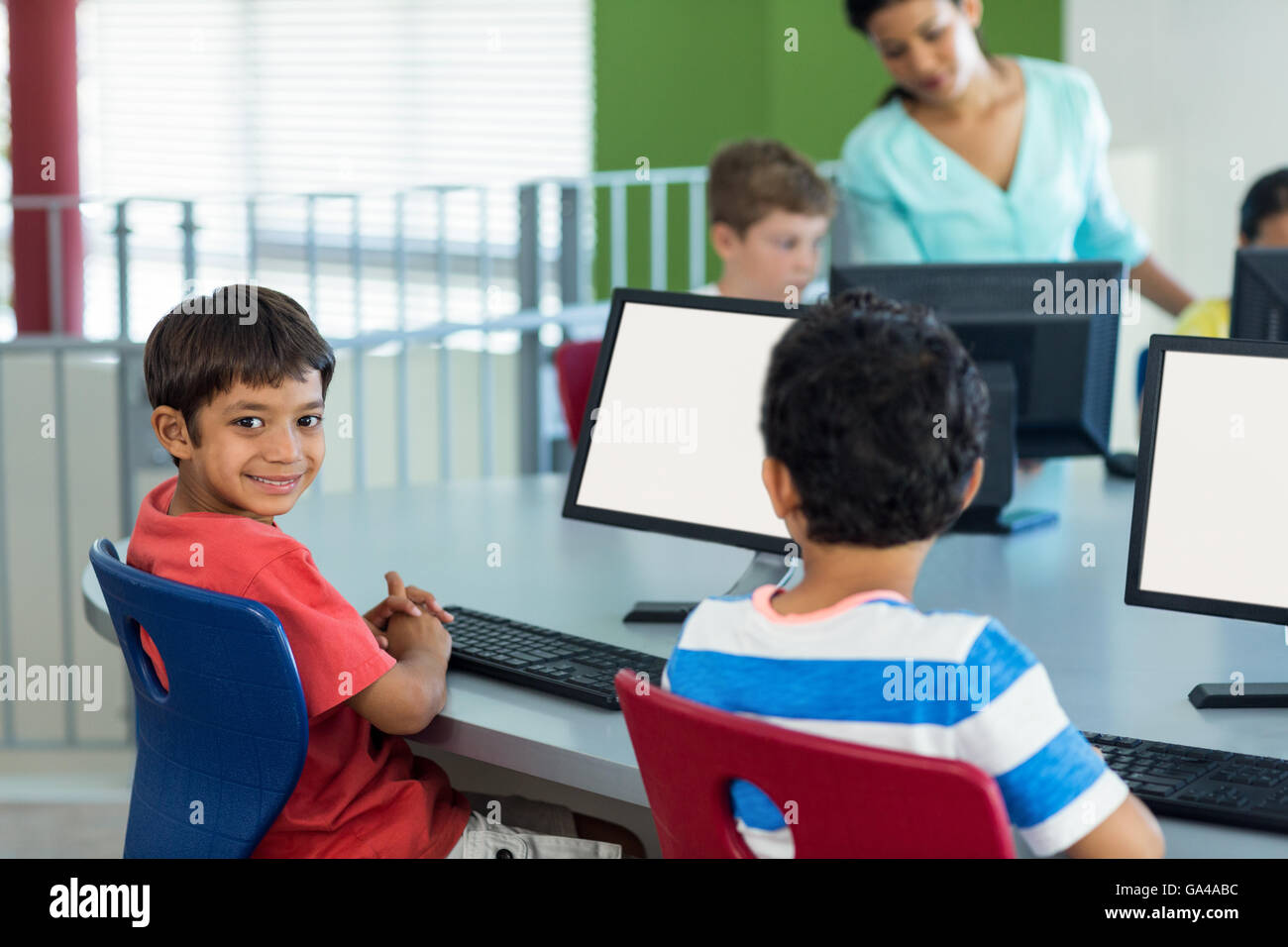 Boy with classmates and teacher during computer class Stock Photo - Alamy