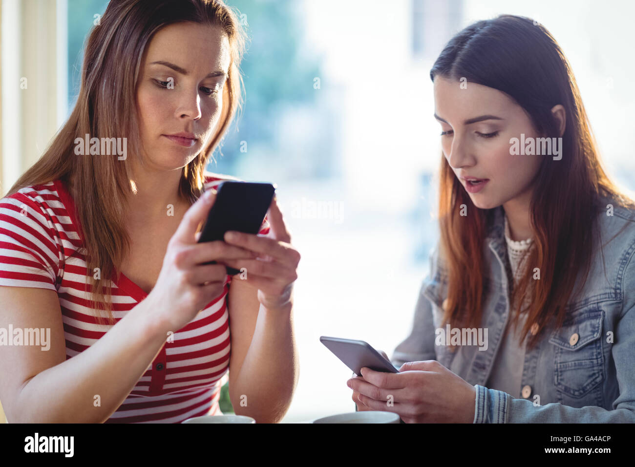 Friends texting on cellphone at cafe Stock Photo - Alamy