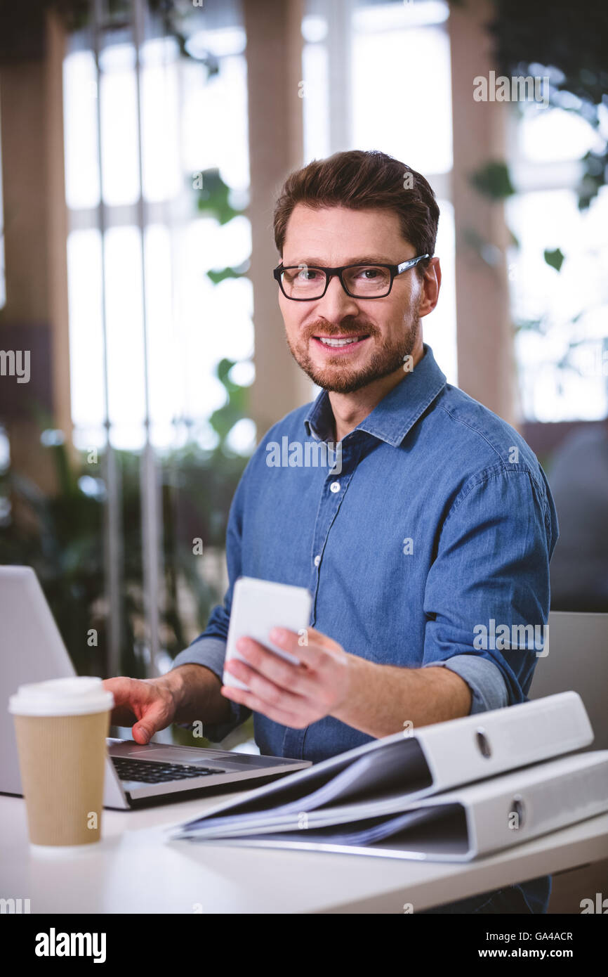 Portrait of confident businessman using cellphone at office Stock Photo ...