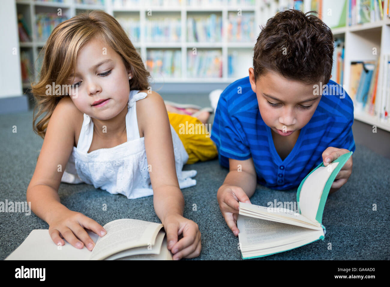 Girl and boy reading books at library in school Stock Photo - Alamy