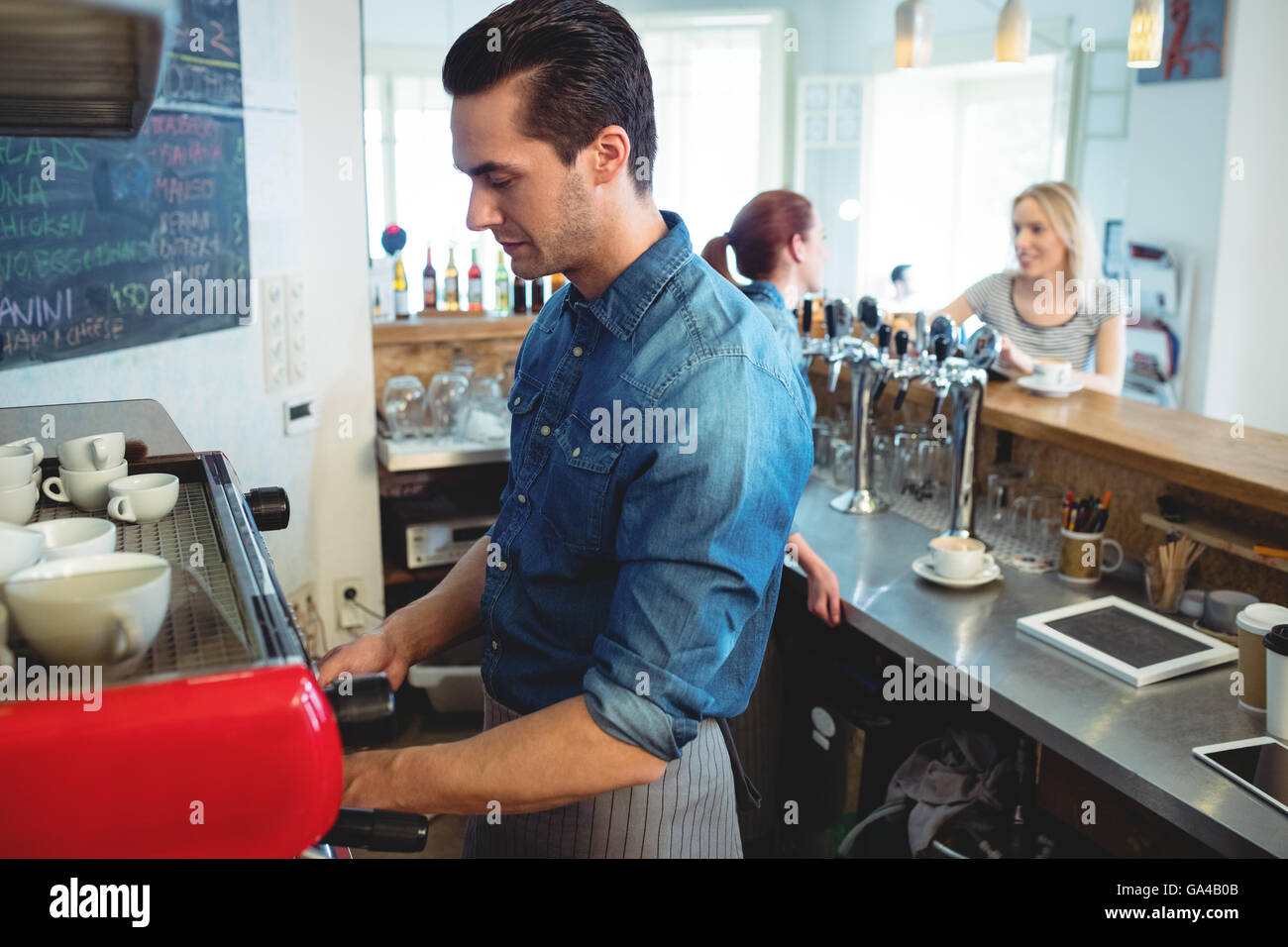 Waiter working while barista talking with customer at cafeteria Stock ...