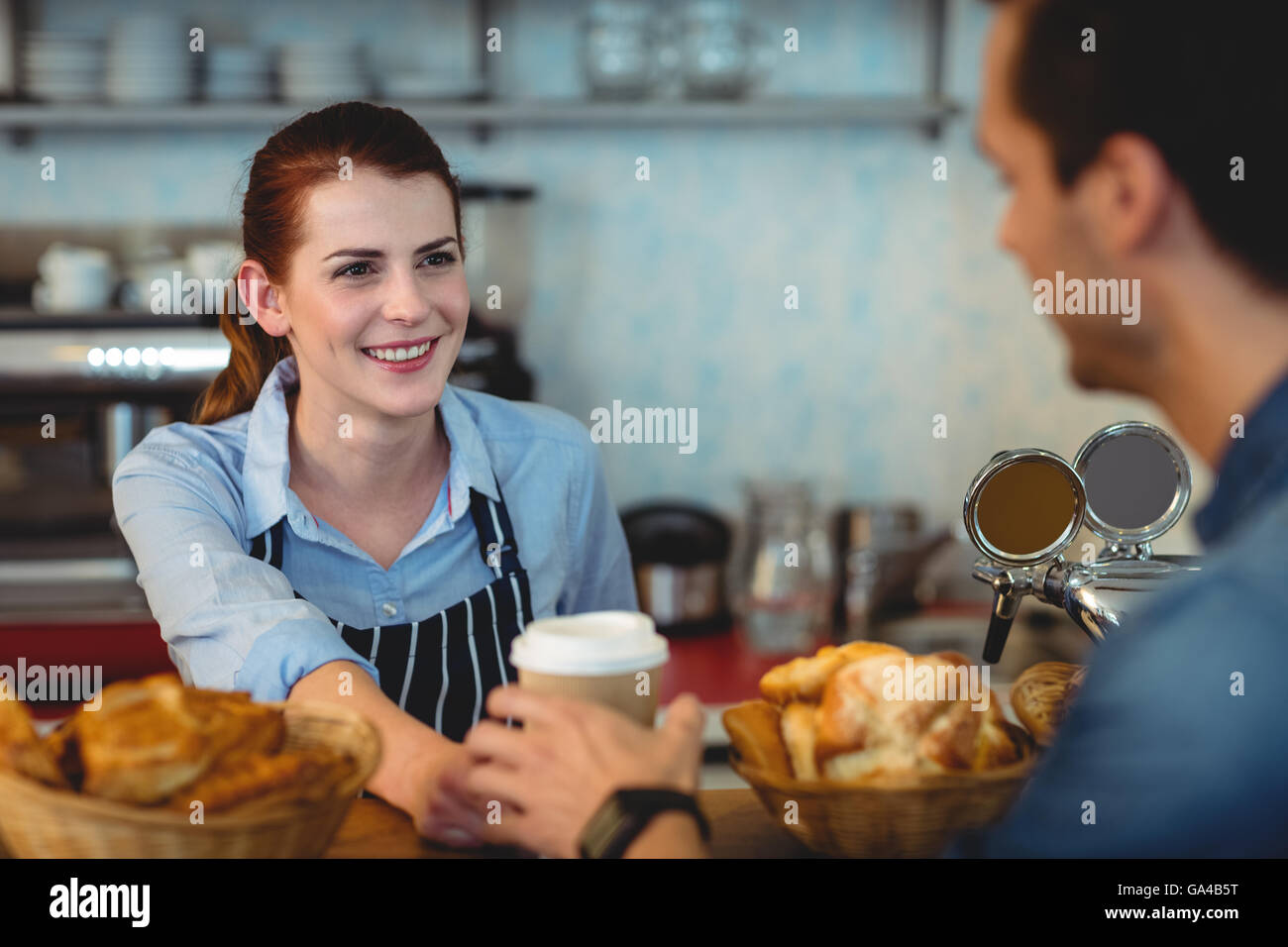 Happy barista offering coffee to customer at cafe Stock Photo - Alamy