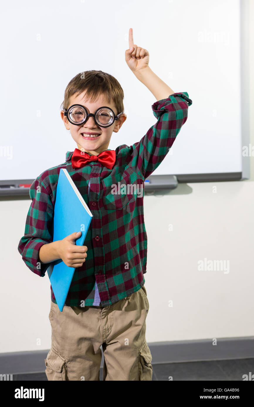 Portrait of cute boy with notebook raising hand in classroom Stock ...