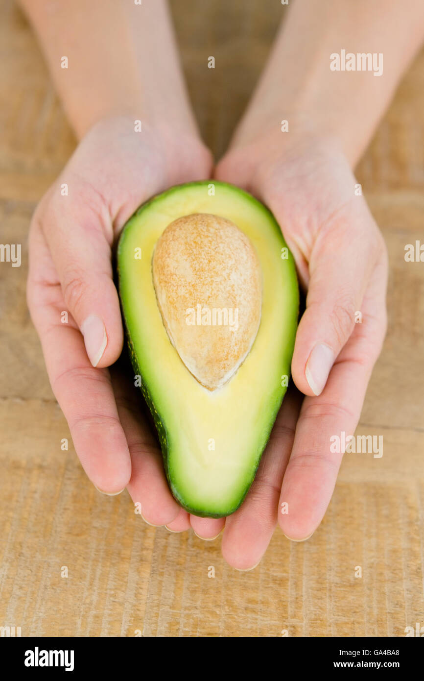 Person holding avocado at table Stock Photo - Alamy