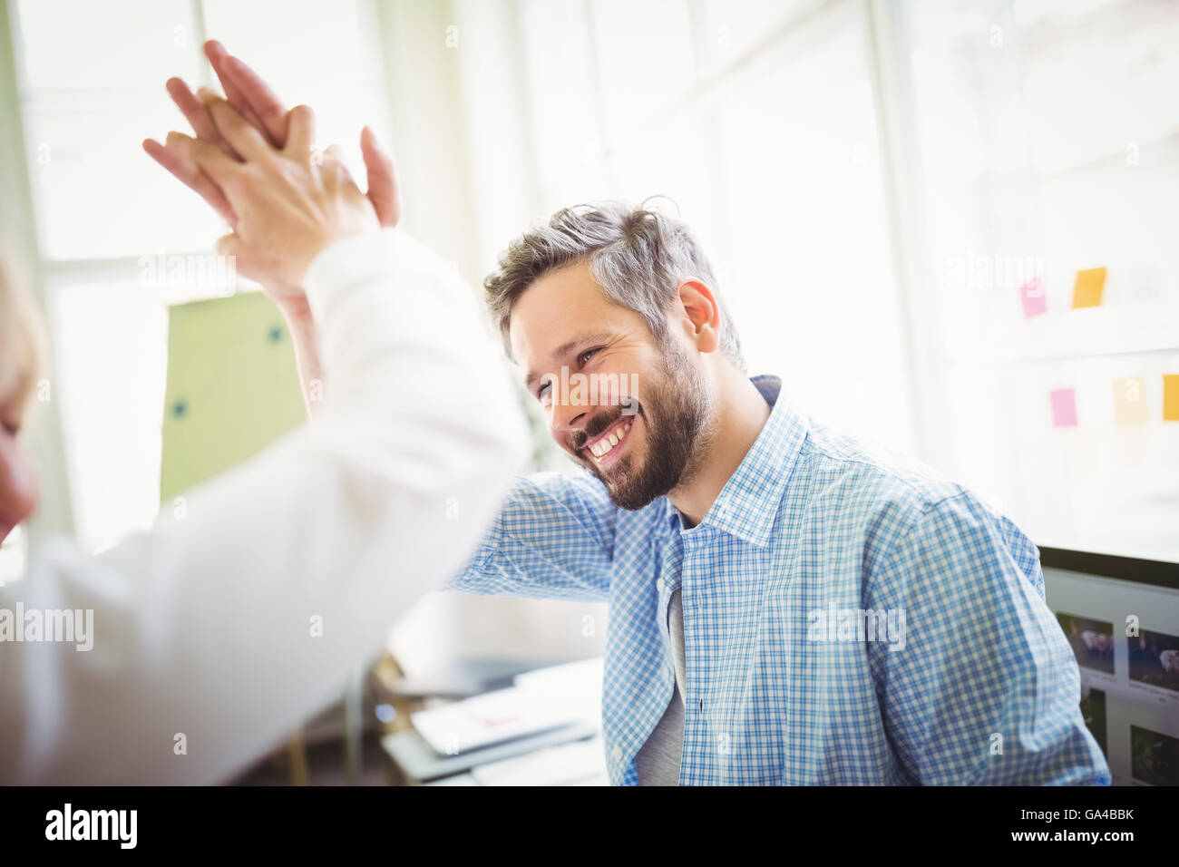 Happy coworkers giving high-five in creative office Stock Photo - Alamy