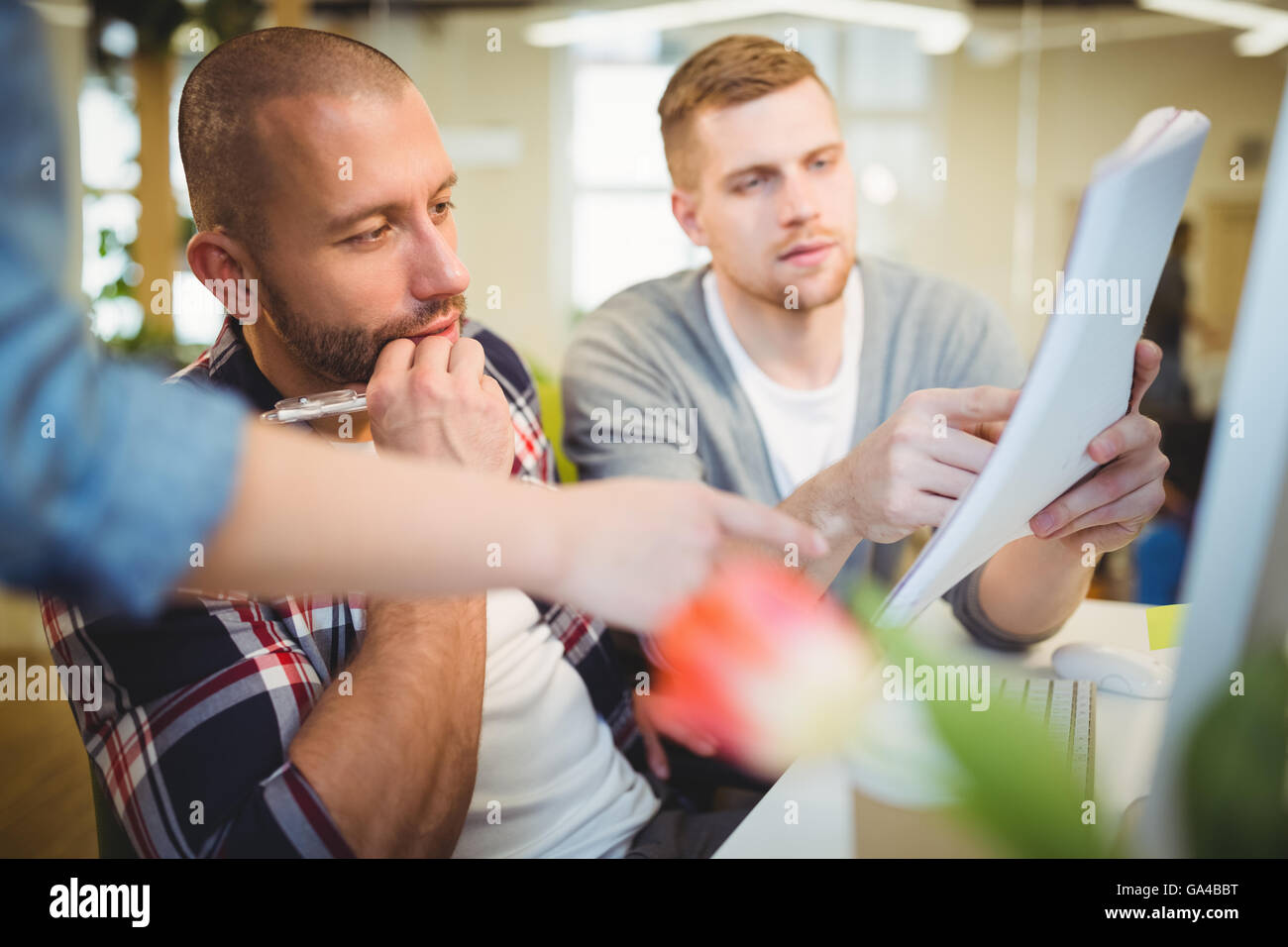 Businessman discussing documents with colleagues in office Stock Photo ...