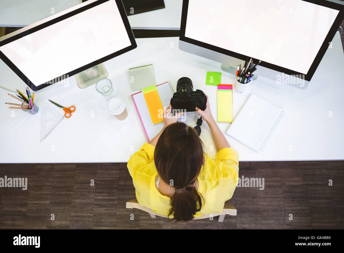 Overhead view of professional sitting with camera at desk in creative ...