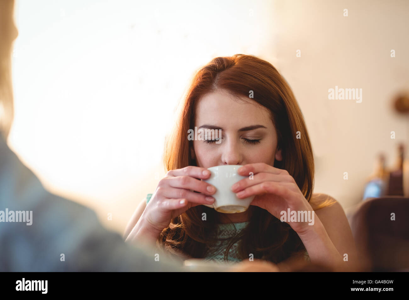 Beautiful woman sipping coffee with friend at cafe Stock Photo - Alamy