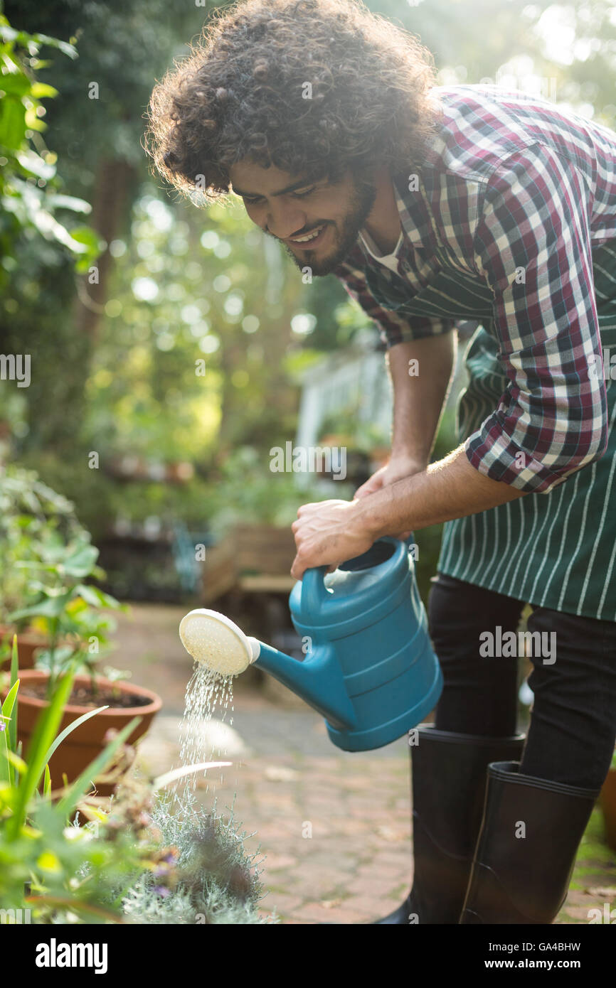 Gardener watering plants outside greenhouse Stock Photo - Alamy