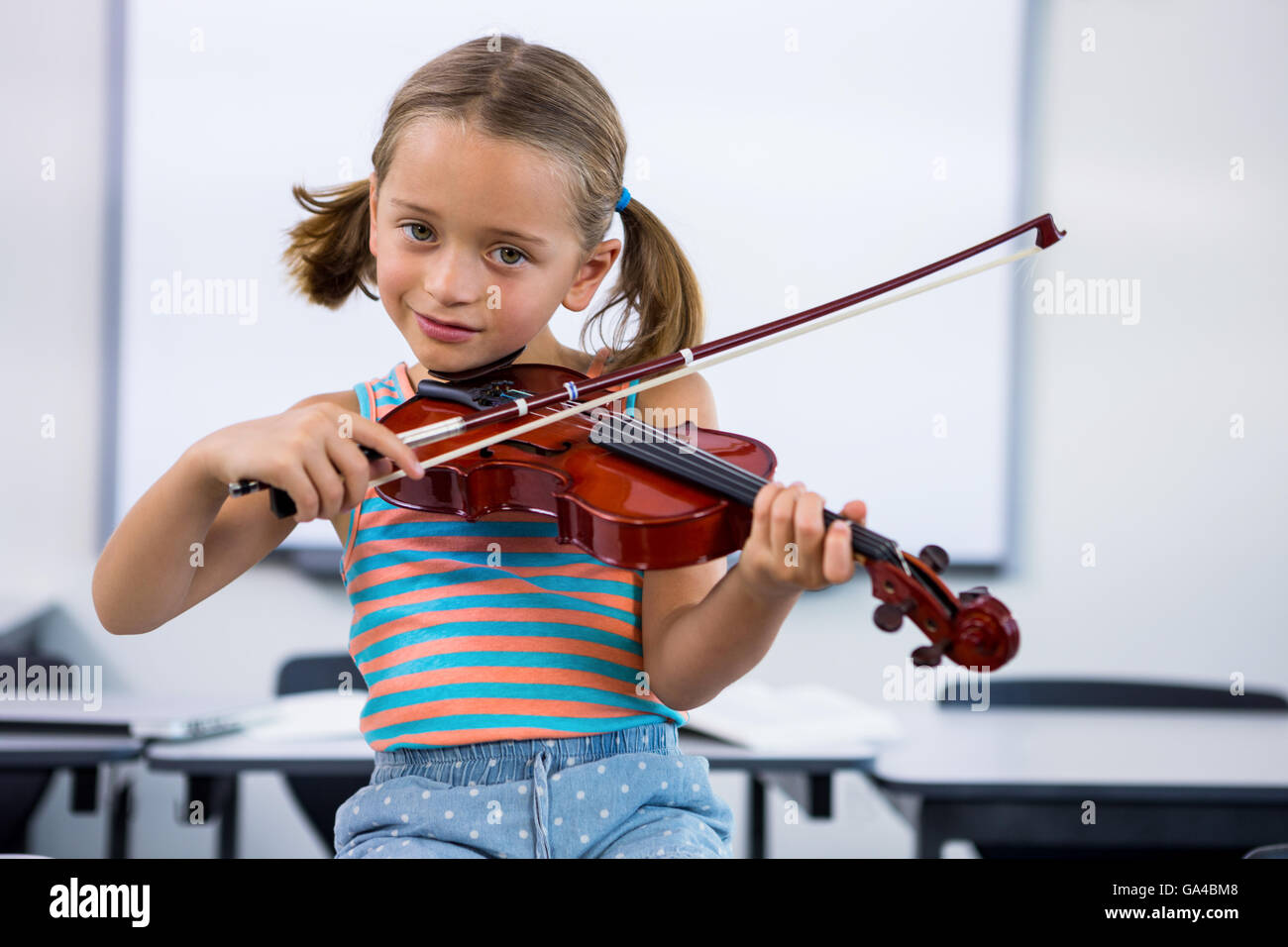 Smiling girl playing violin in classroom Stock Photo - Alamy