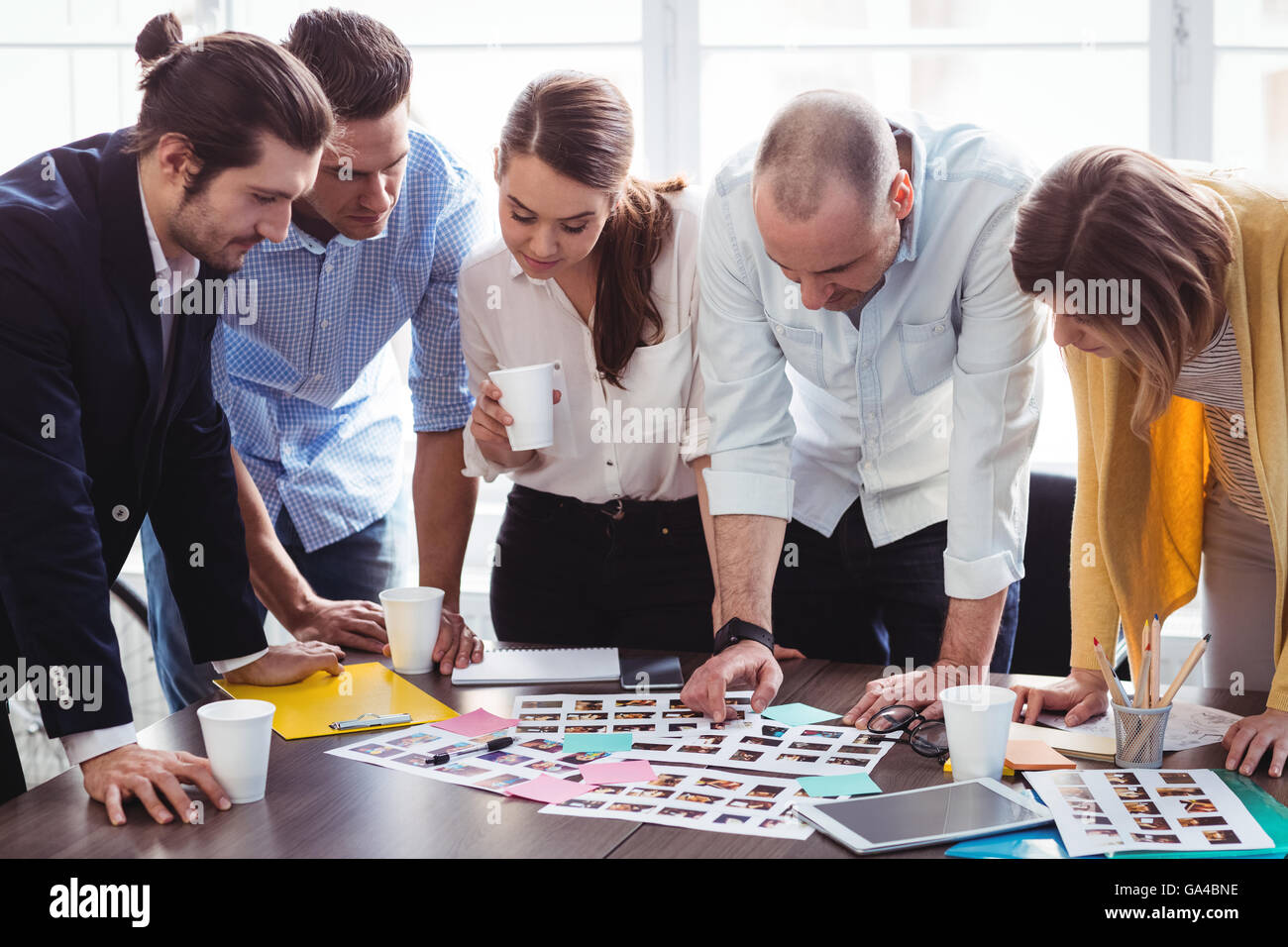 Photo editors looking at photos on table Stock Photo - Alamy