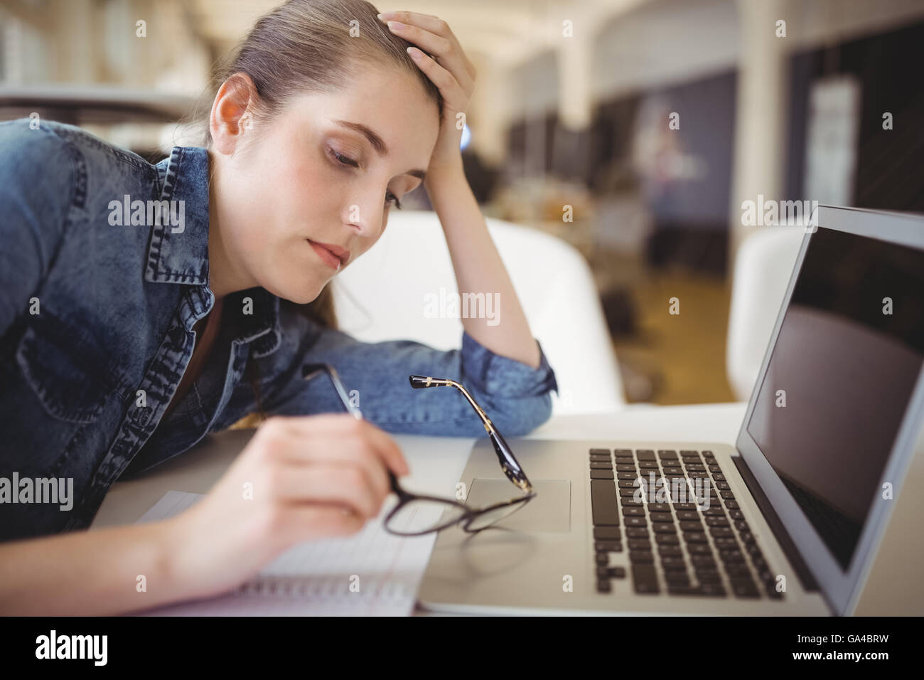 Stressed businesswoman holding eyeglasses in creative office Stock ...