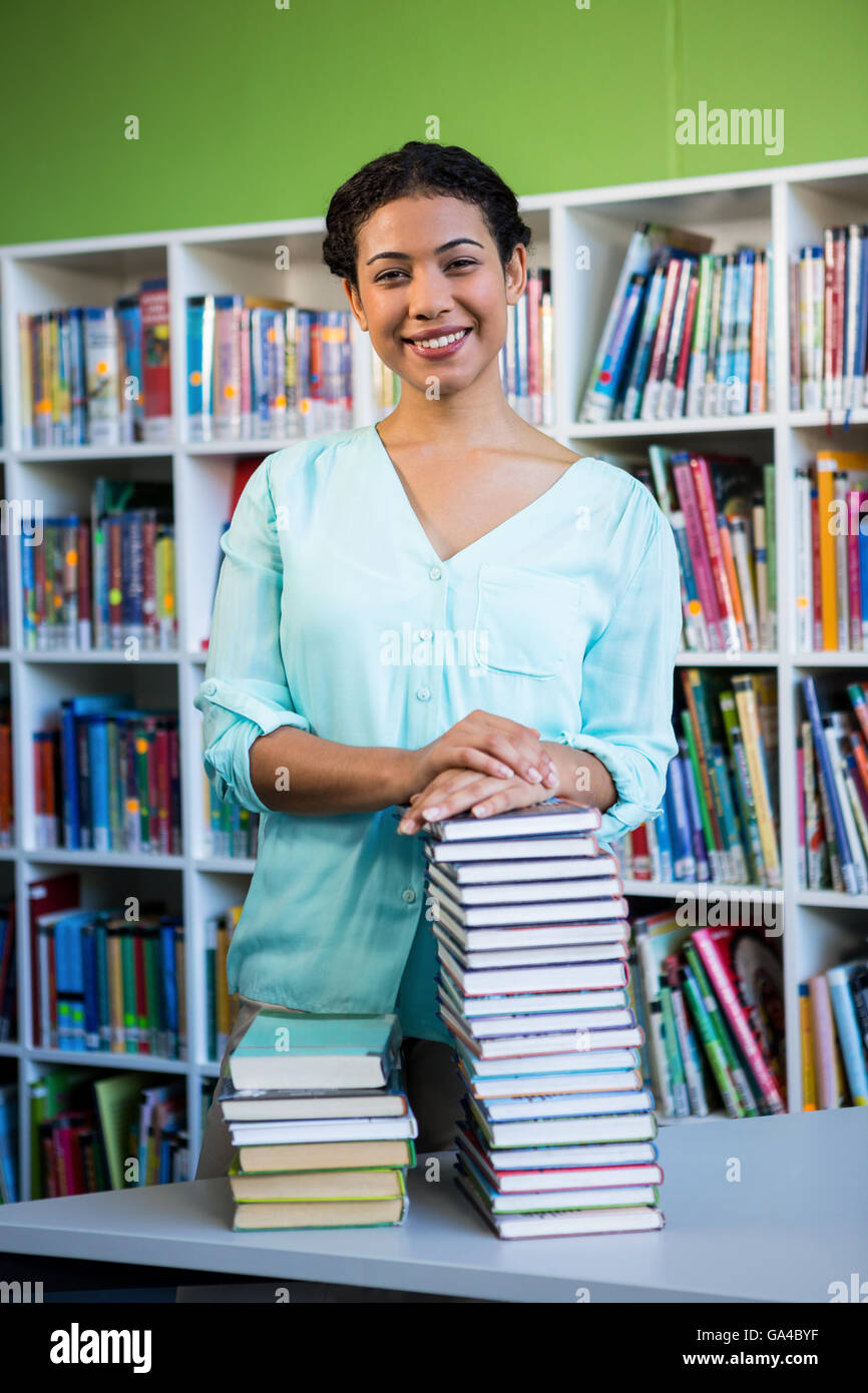 Young woman standing against bookshelf in library Stock Photo - Alamy