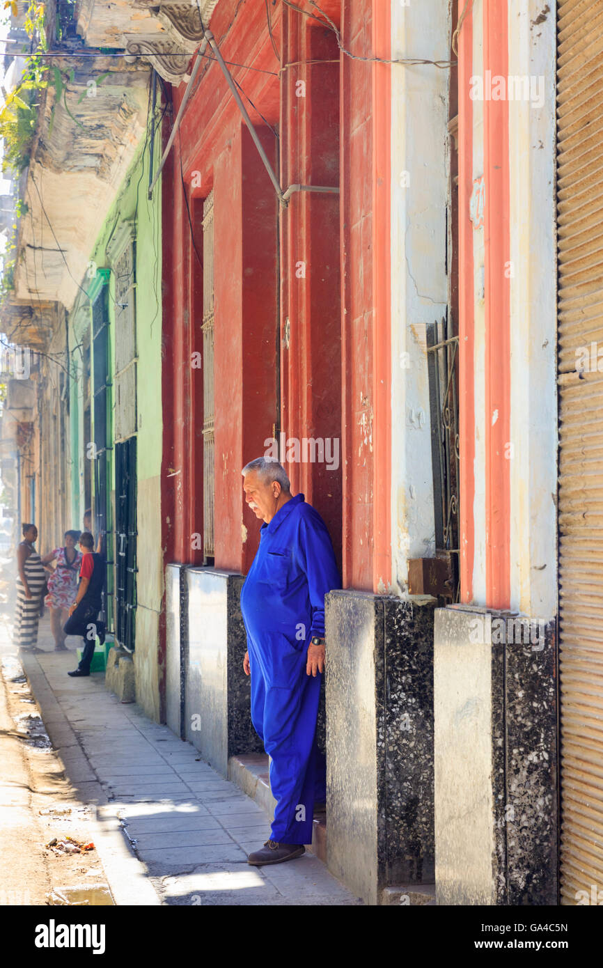 Havana street scene - Cuban man in blue workman's overalls leaning on a ...