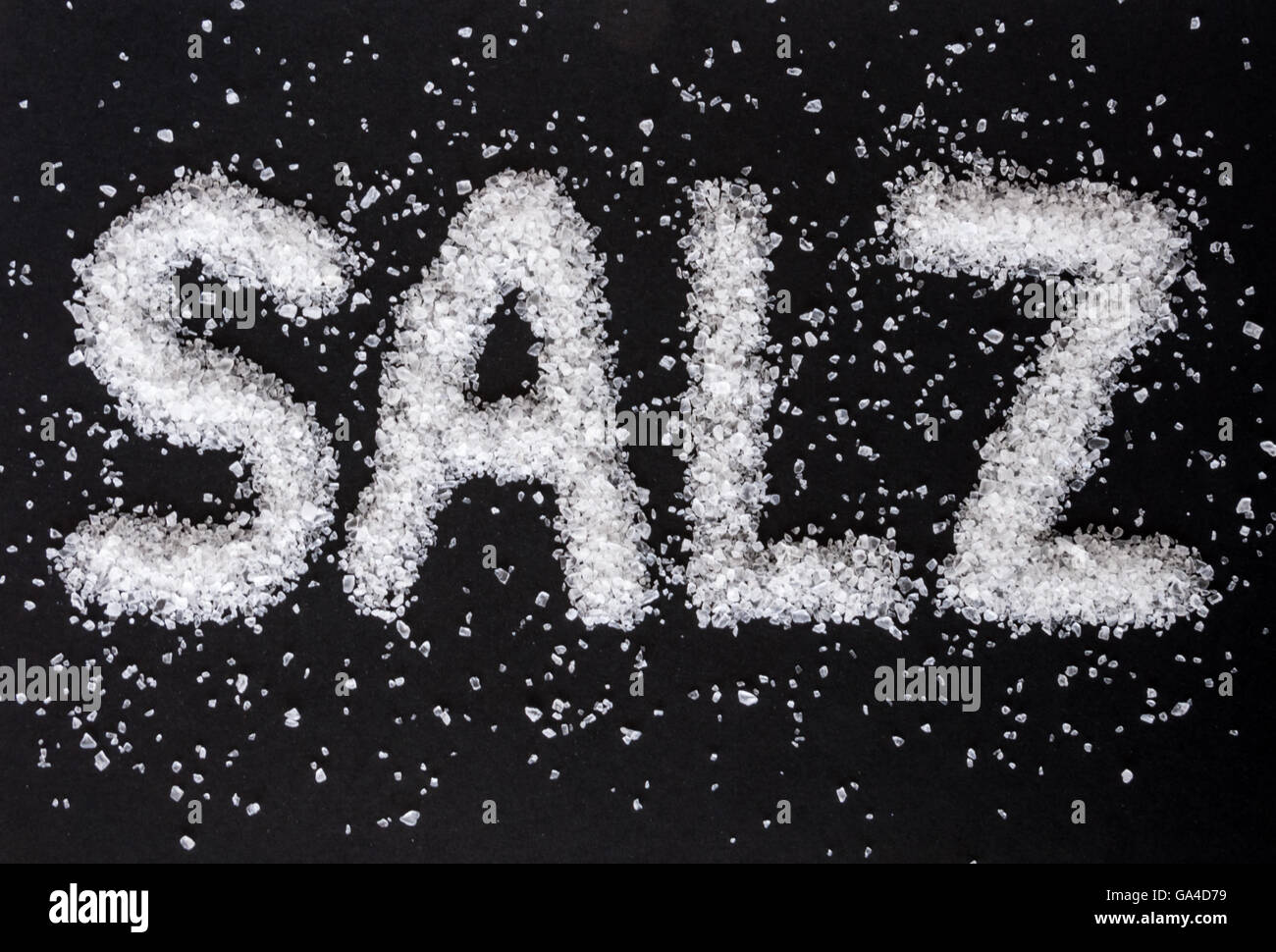 Coarse-grained sea salt with the German word SALZ on black background ...