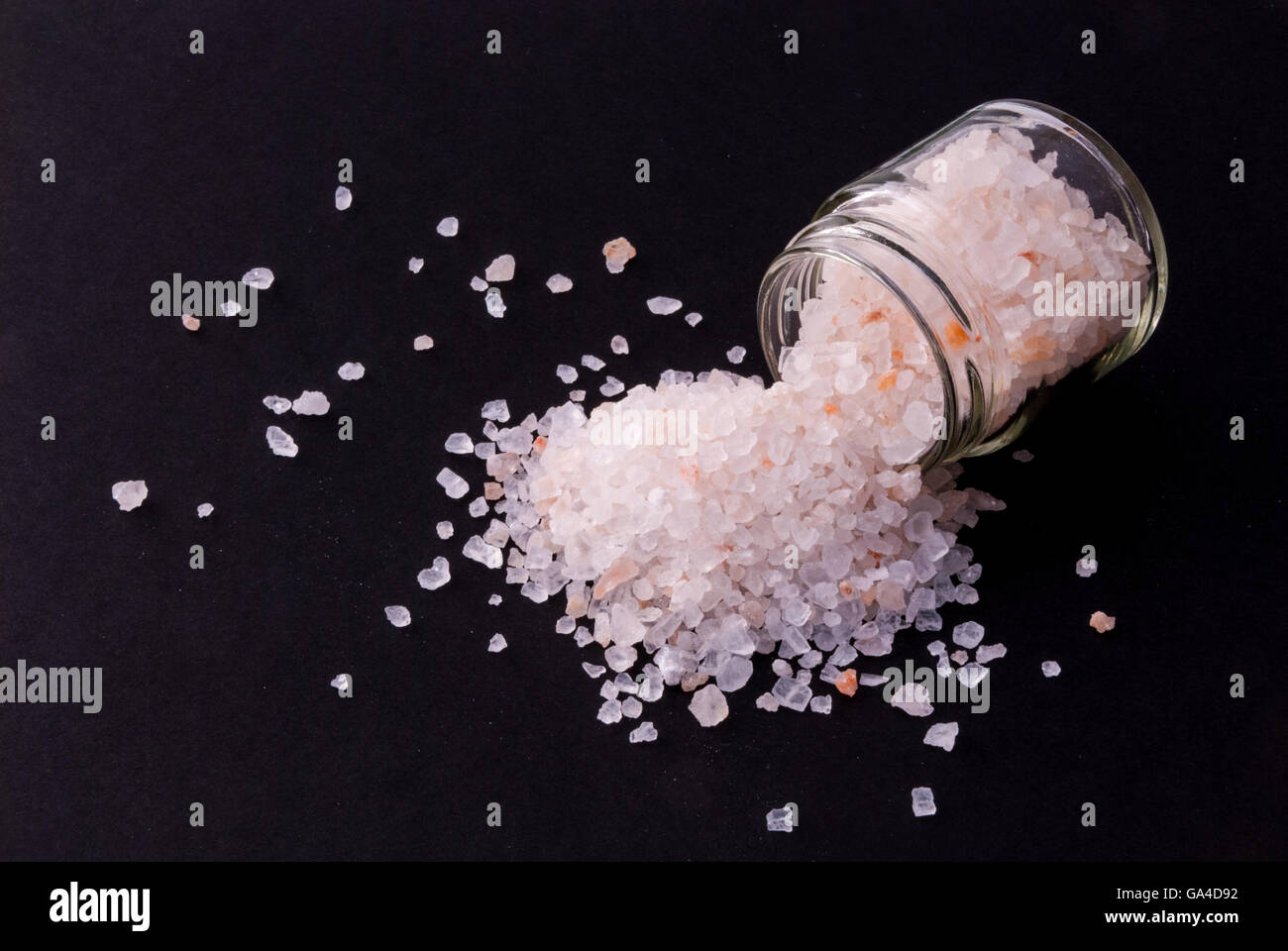 Coarse-grained salt from the Himalyas in a glass on black background ...