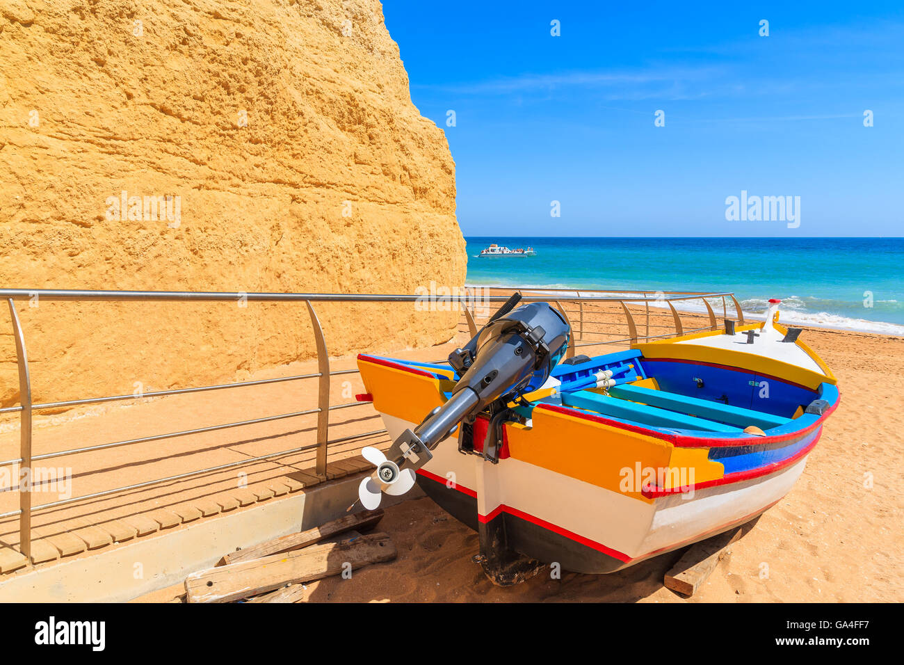 Typical colorful fishing boat on sandy Benagil beach in Algarve region ...