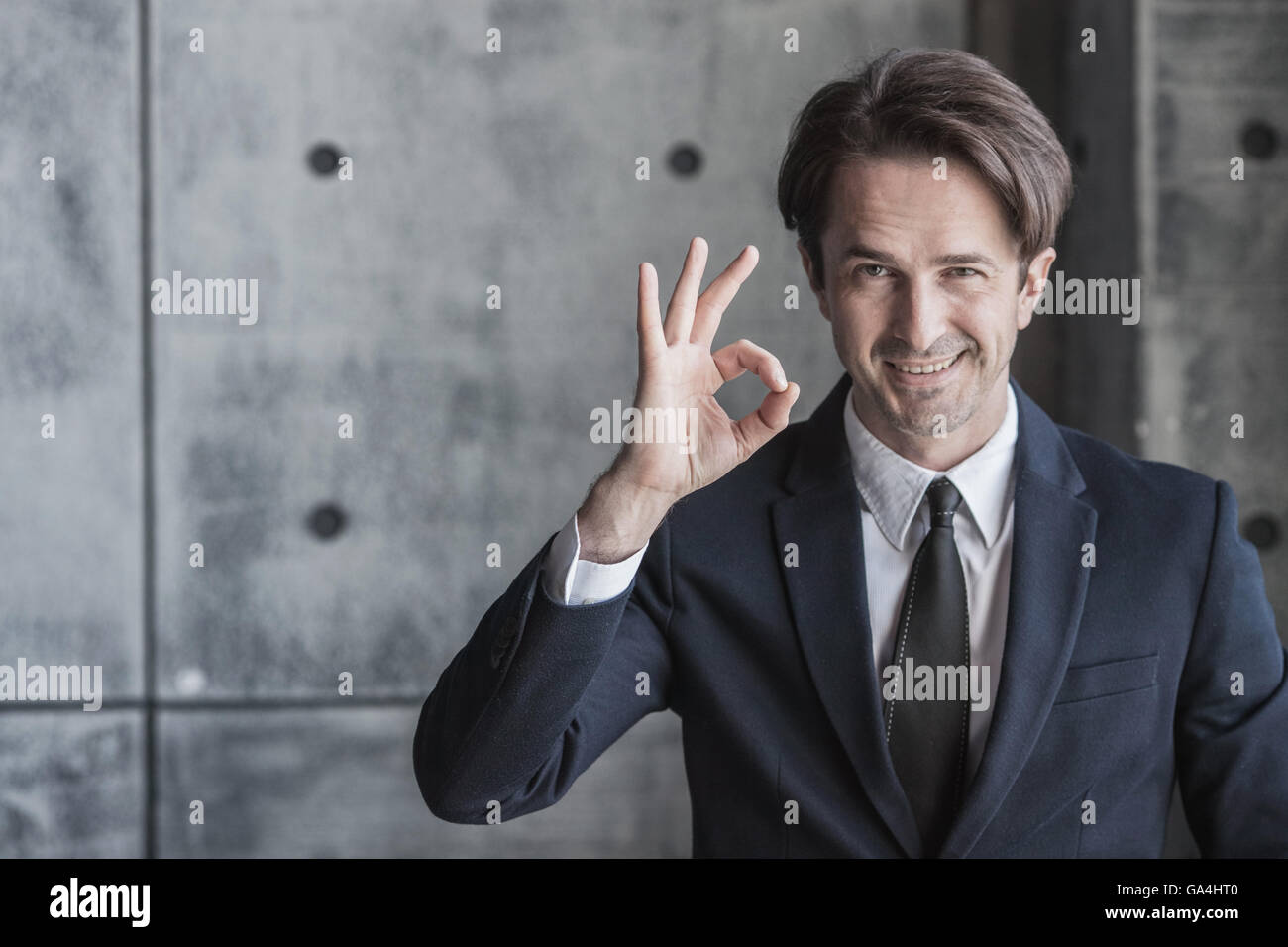 Businessman smiling and showing OK sign Stock Photo - Alamy