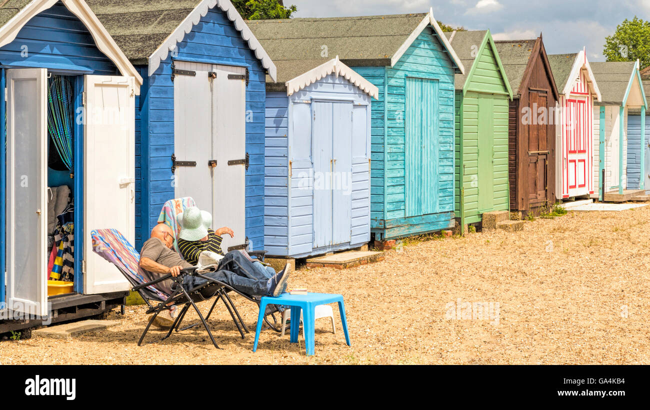 Sunbathing couple in front of their beach hut in West Mersea, Mersea ...