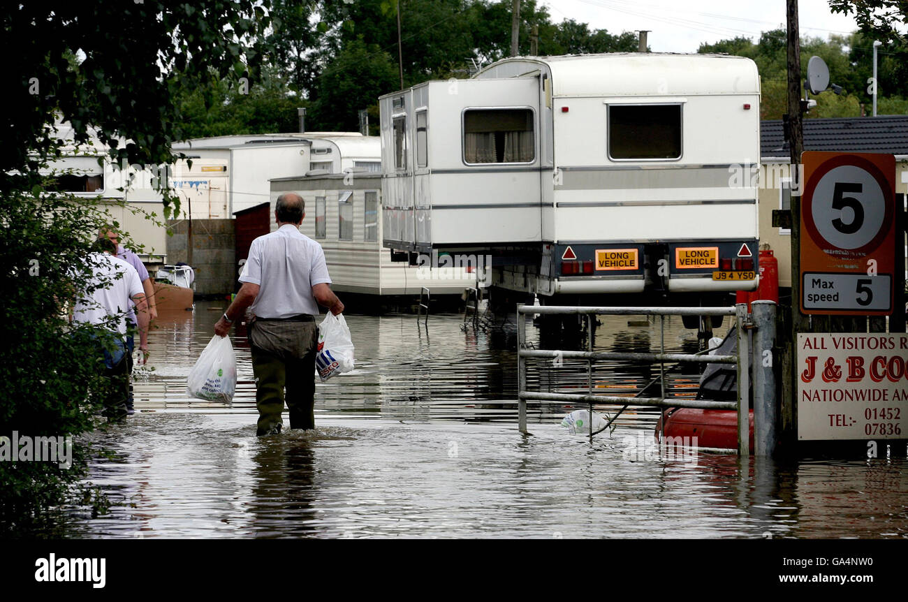 A man carries supplies into a flooded caravan park close to the river ...
