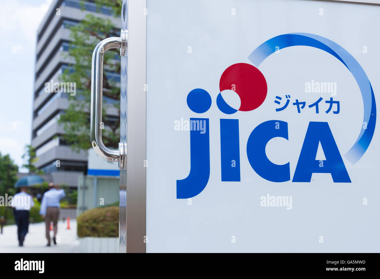 Pedestrians walk past a JICA signboard on display outside its Ichigaya ...