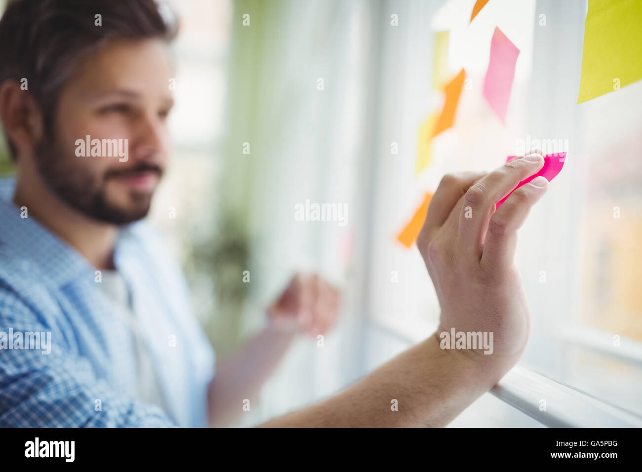 Businessman sticking adhesive notes on glass window at creative office ...