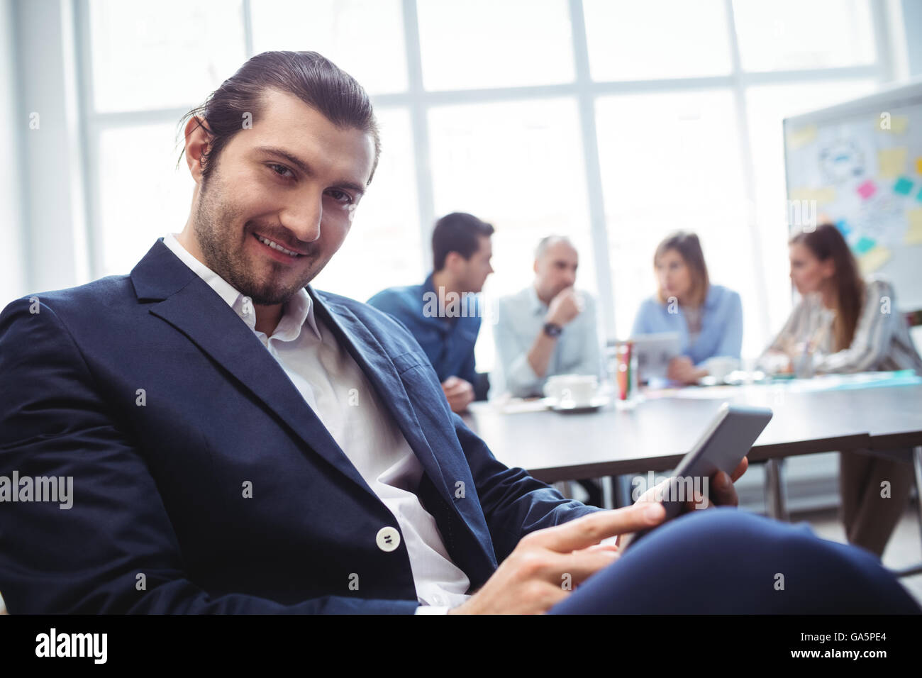 Smiling businessman using digital tablet against colleagues Stock Photo ...
