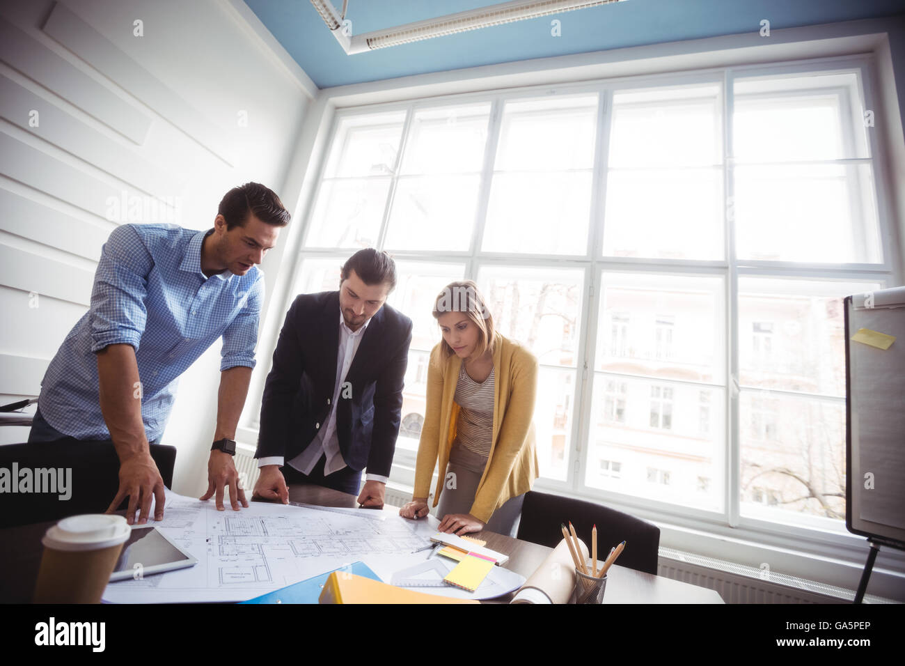 Business people looking at blueprint on table Stock Photo - Alamy