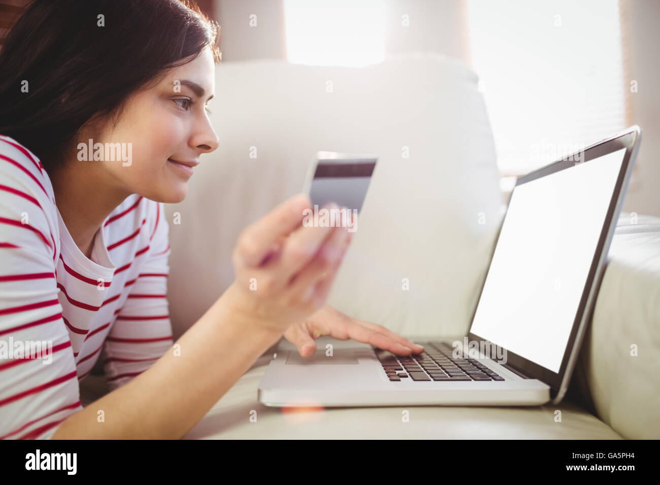 Woman using laptop on couch Stock Photo - Alamy