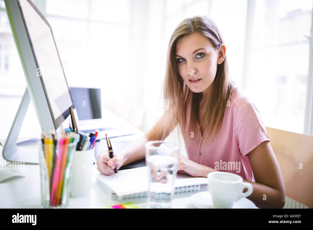 Beautiful graphic designer writing document at desk Stock Photo - Alamy