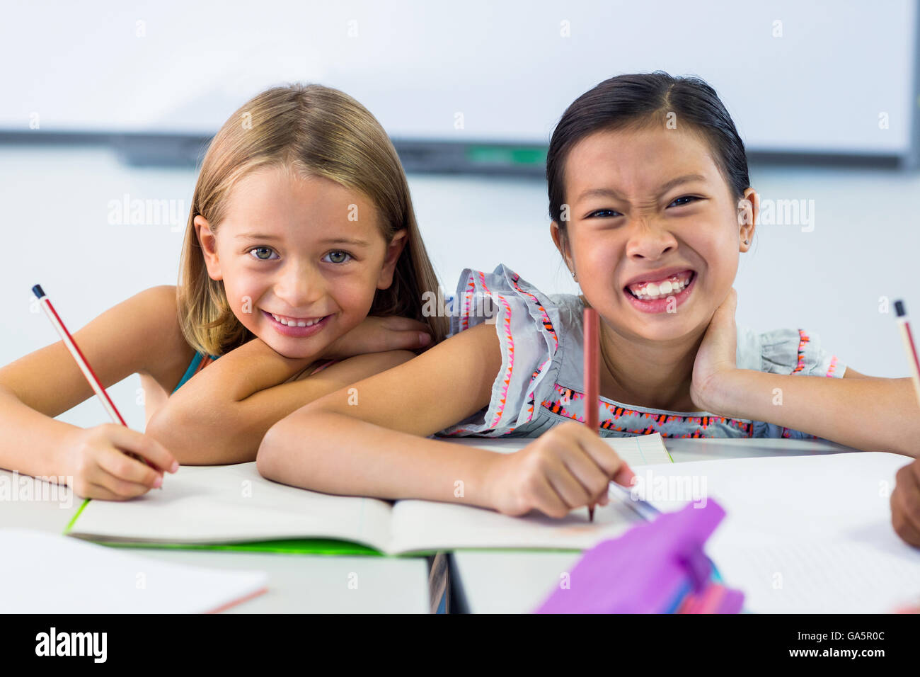 Smiling schoolgirls writing on books Stock Photo - Alamy