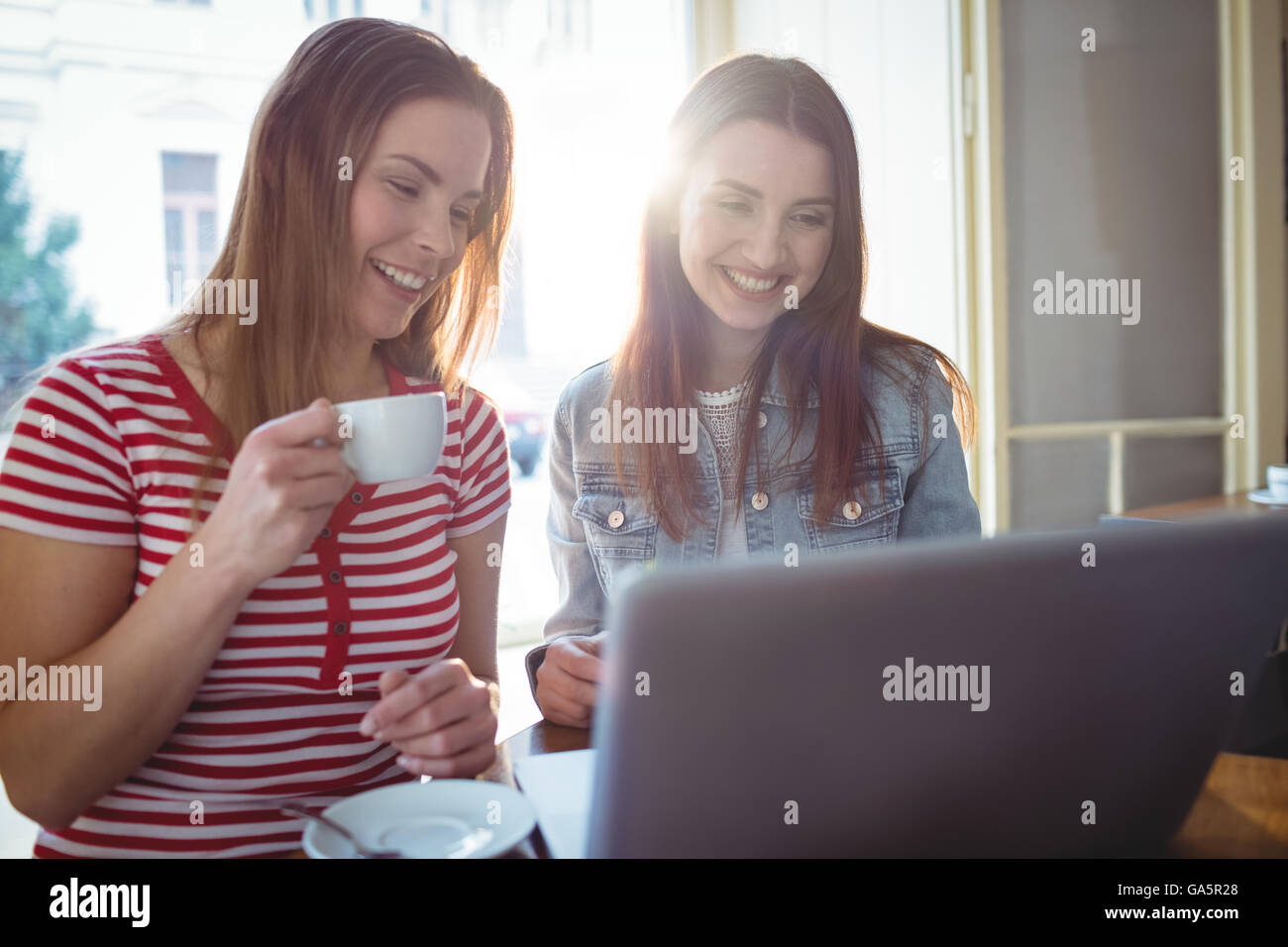 Happy friends using laptop at cafe Stock Photo - Alamy