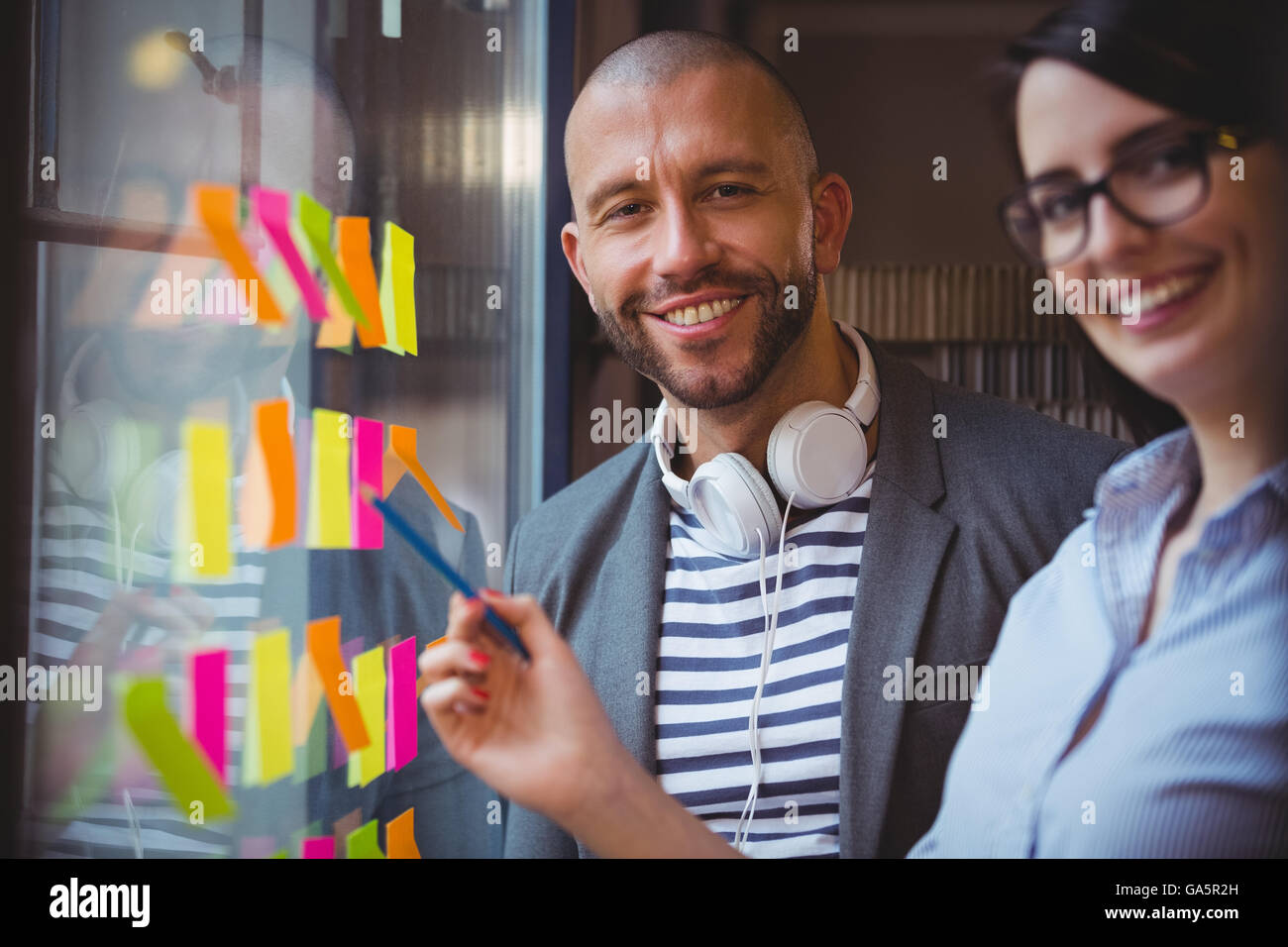 Business people smiling while standing by sticky notes Stock Photo - Alamy