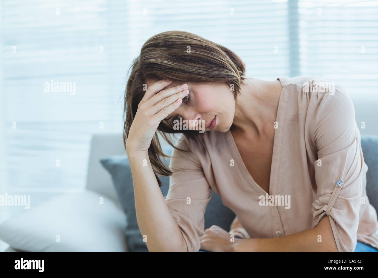 Sad woman sitting on sofa Stock Photo - Alamy