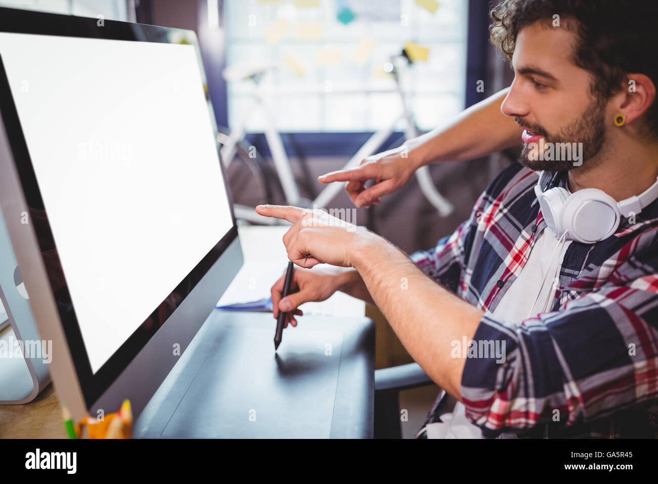 Graphic designer pointing at computer monitor in creative office Stock ...