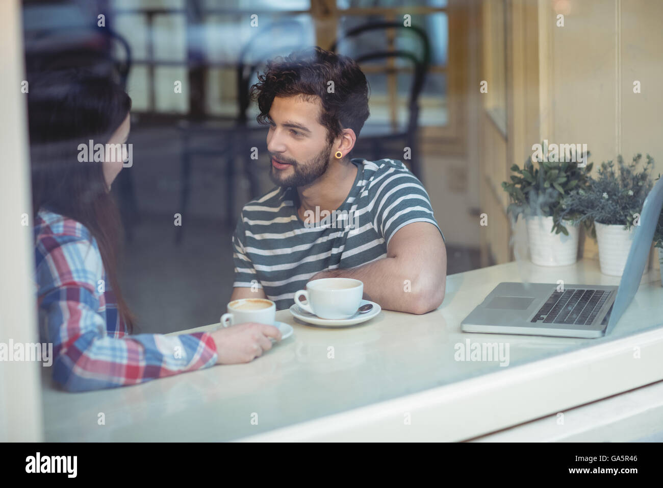 Couple talking while sitting by window at cafe Stock Photo - Alamy